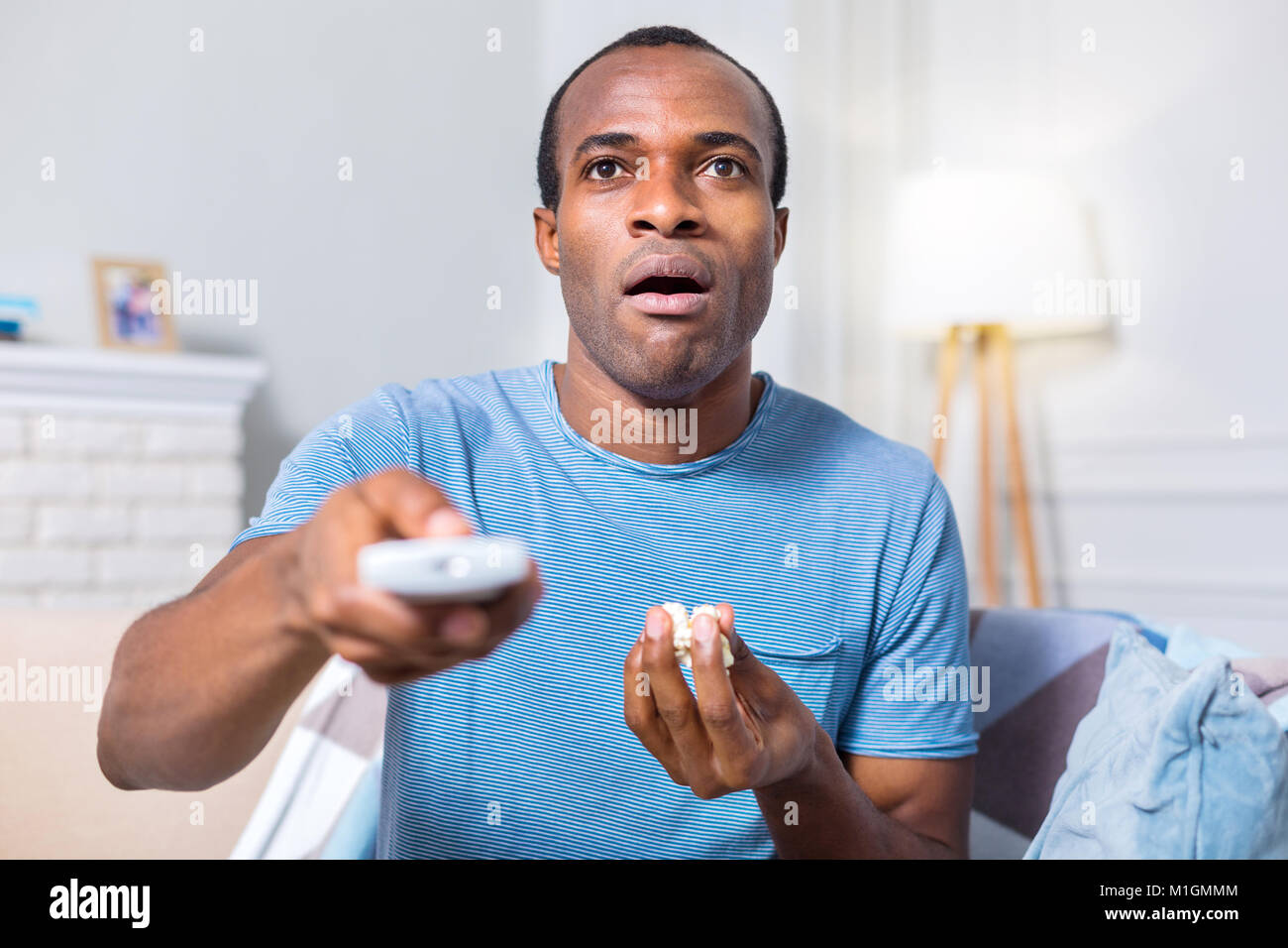 Handsome young man using remote control Stock Photo - Alamy