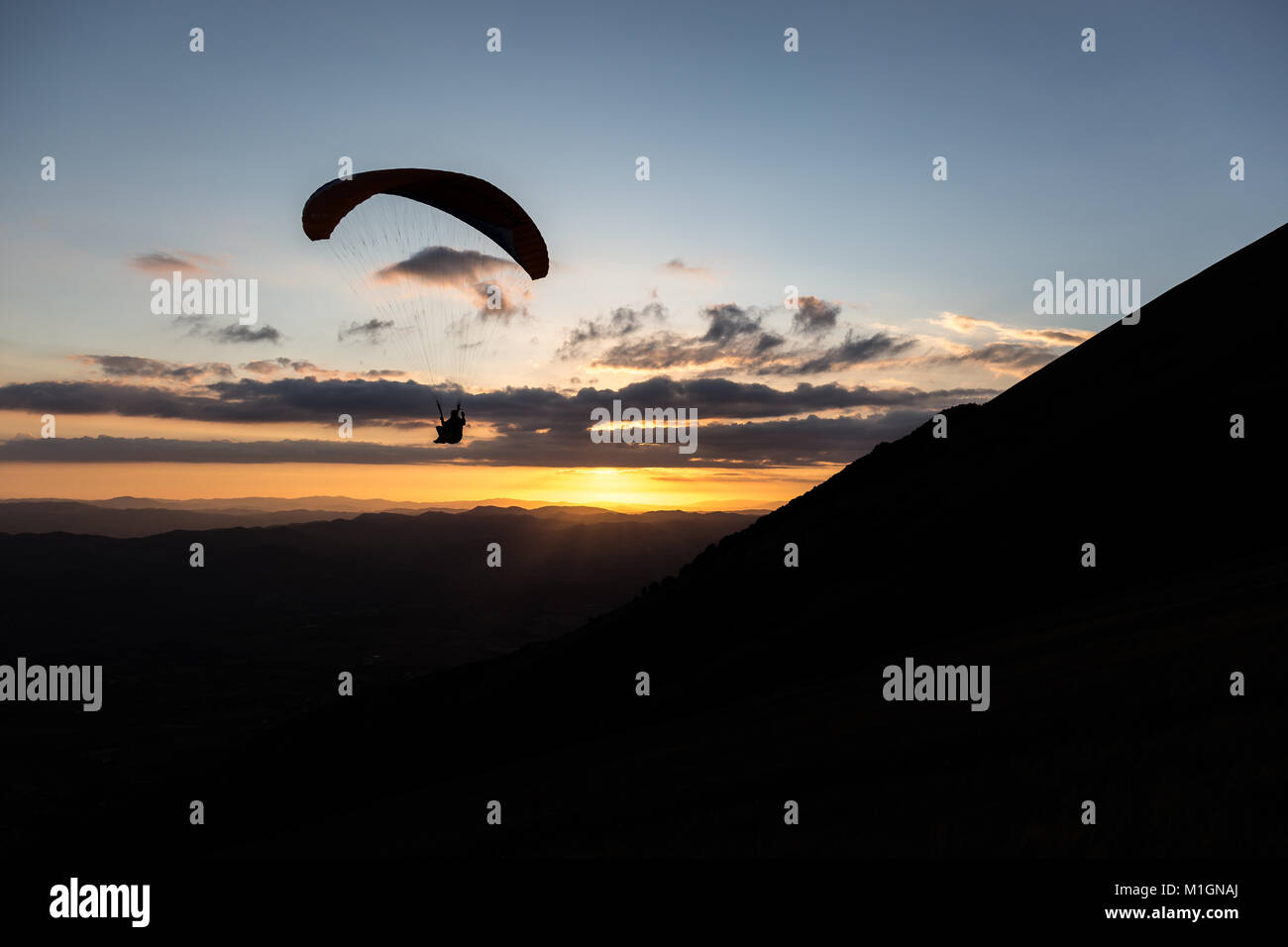 Beautiful shot of a paraglider silhouette flying over Monte Cucco ...