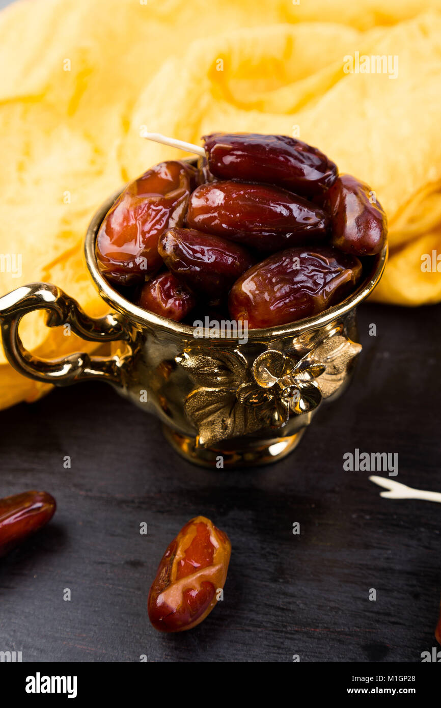 Dry fruit dates in golden cup near slate black heart. Copy space Stock ...