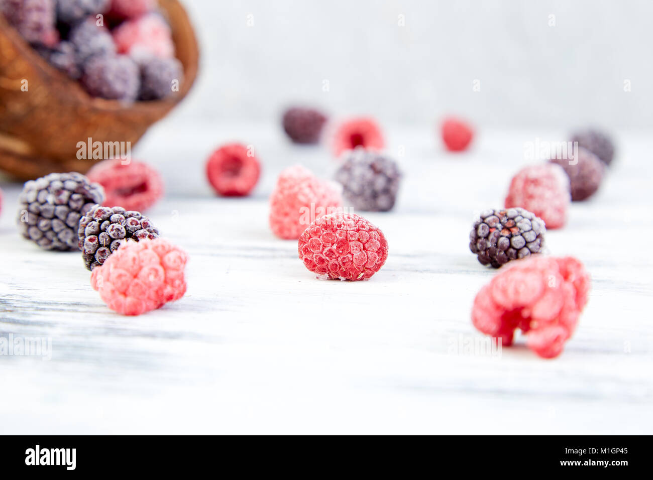 Frozen black and red raspberries in coconut bowl Stock Photo - Alamy