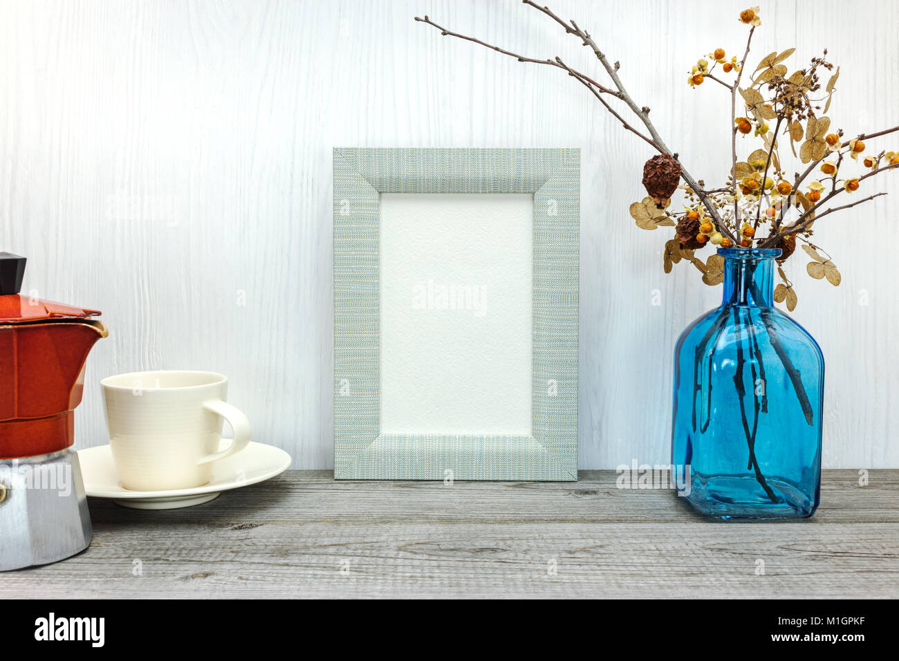 coffee pot, cup, empty photo frame and vase with pressed flowers on ...