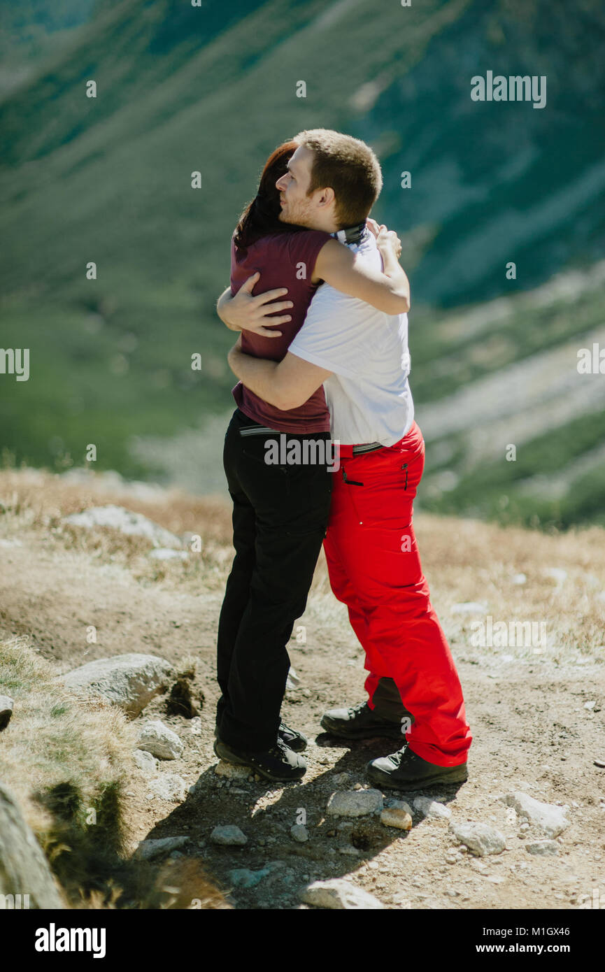 Portrait of a young couple embracing in nature on top of mountains ...