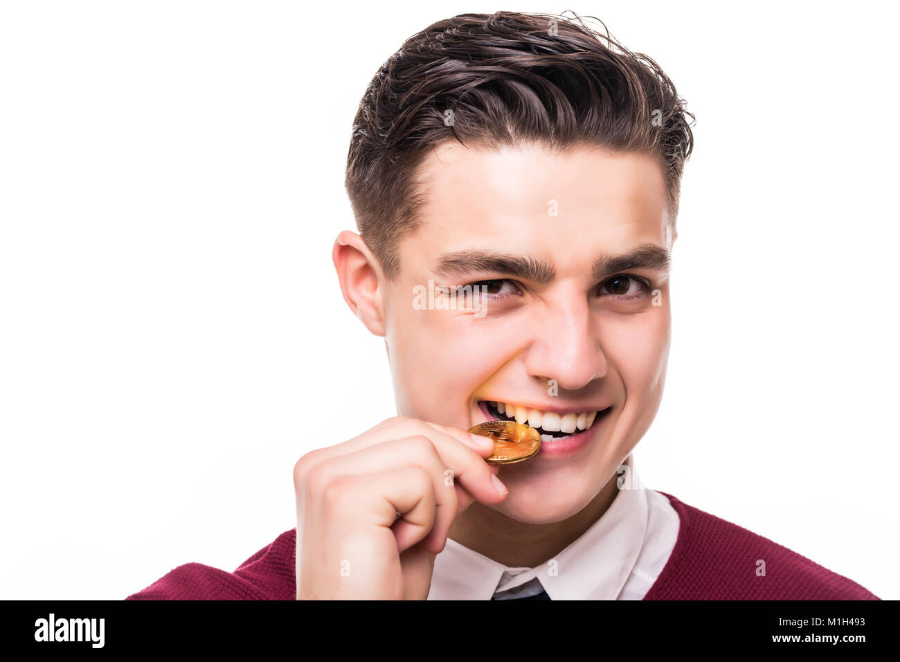 Portrait of a man biting golden bitcoin isolated over white background ...