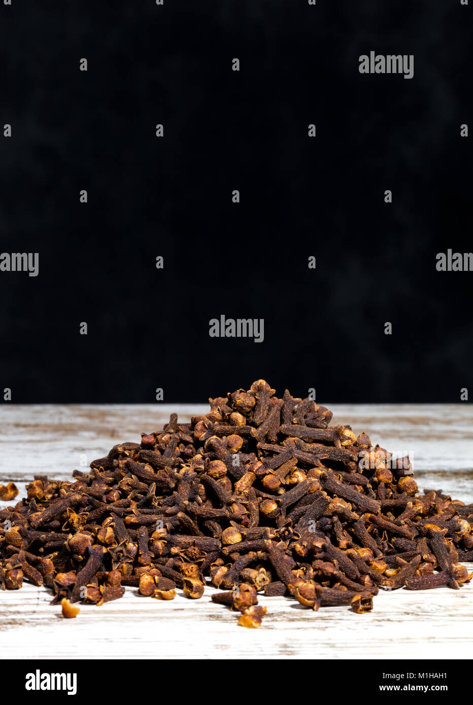 cloves on an old wooden table, dark and non uniform wall as background ...
