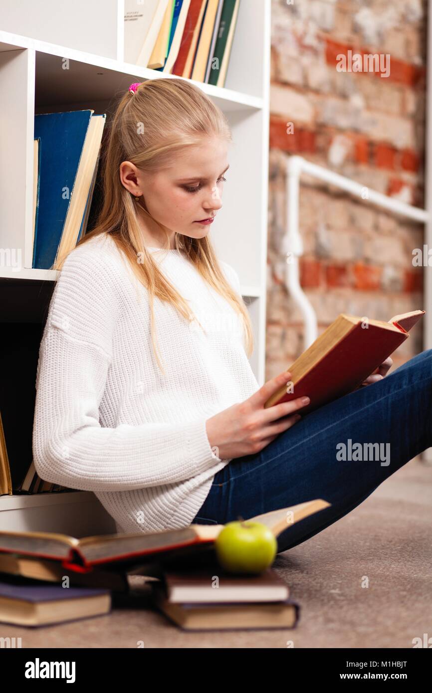 Teenage girl reading a book in library Stock Photo - Alamy
