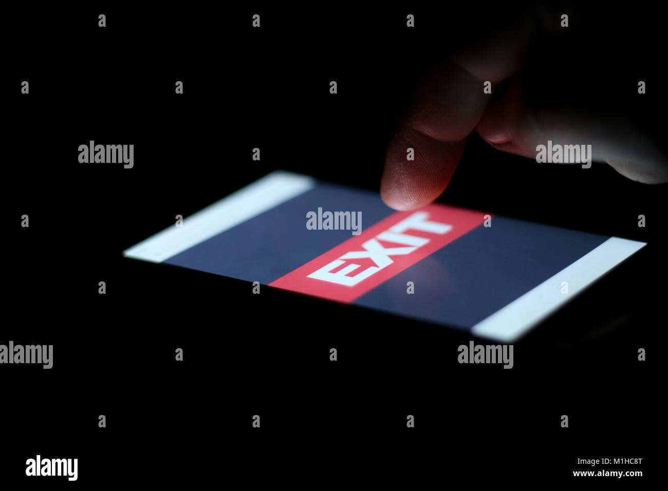 A finger touches the exit sign on the display of the phone. A symbol of ...