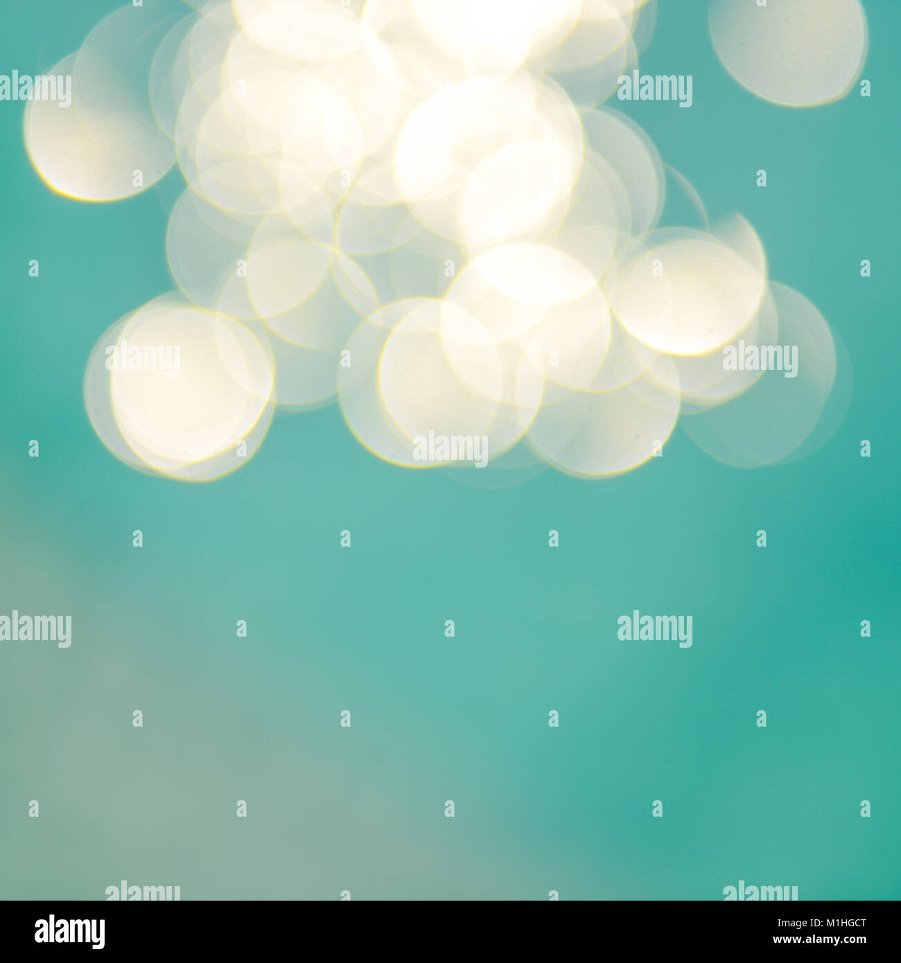 Soft focus bokeh light effects over a rippled, blue water background in ...