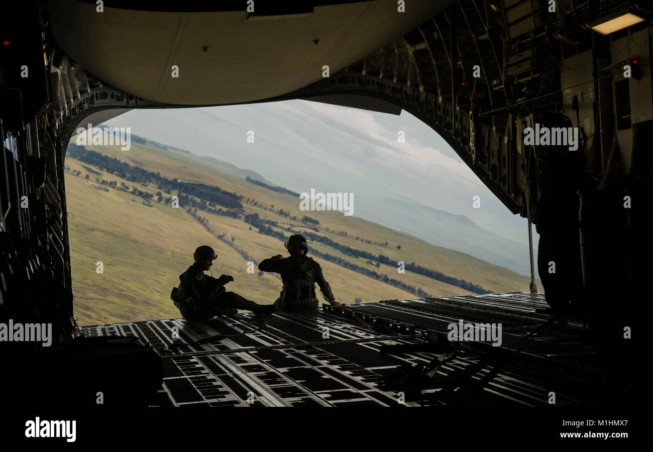 Members of the flight crew monitor a cargo pallet during an airdrop ...