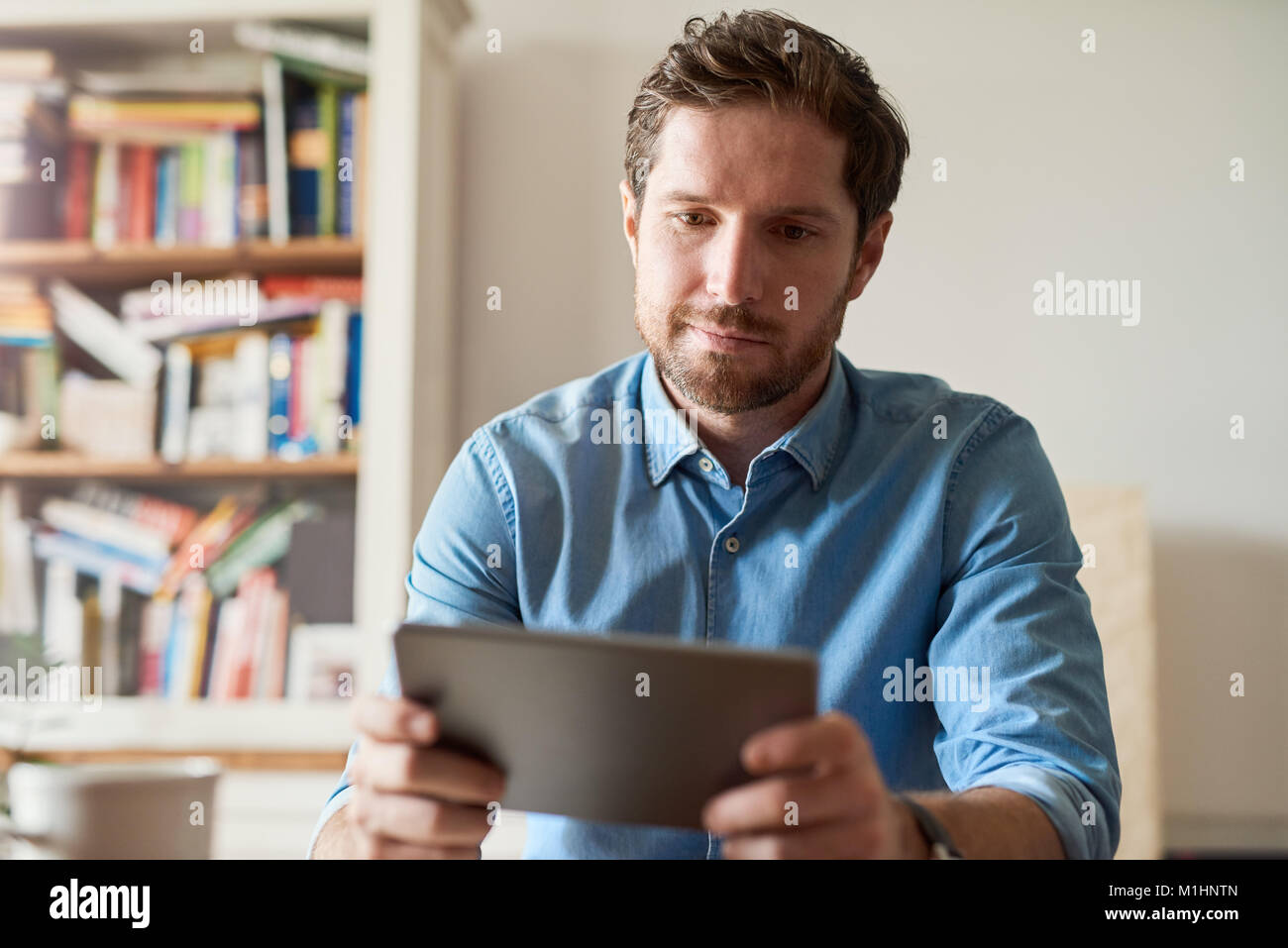 Young man working from home using a digital tablet Stock Photo - Alamy