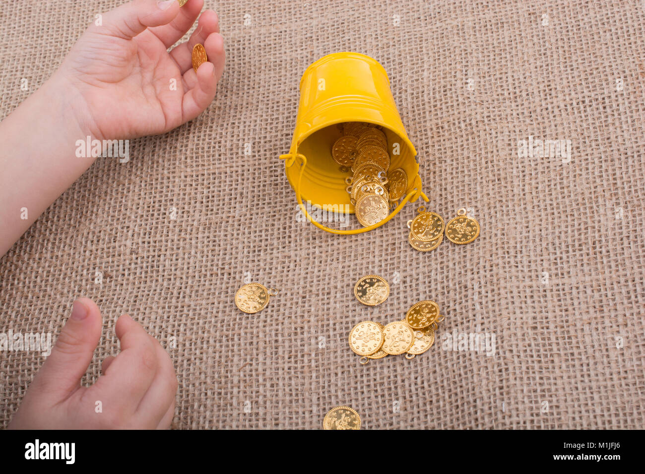 Bucket and fake gold coins in hand on canvas background Stock Photo - Alamy