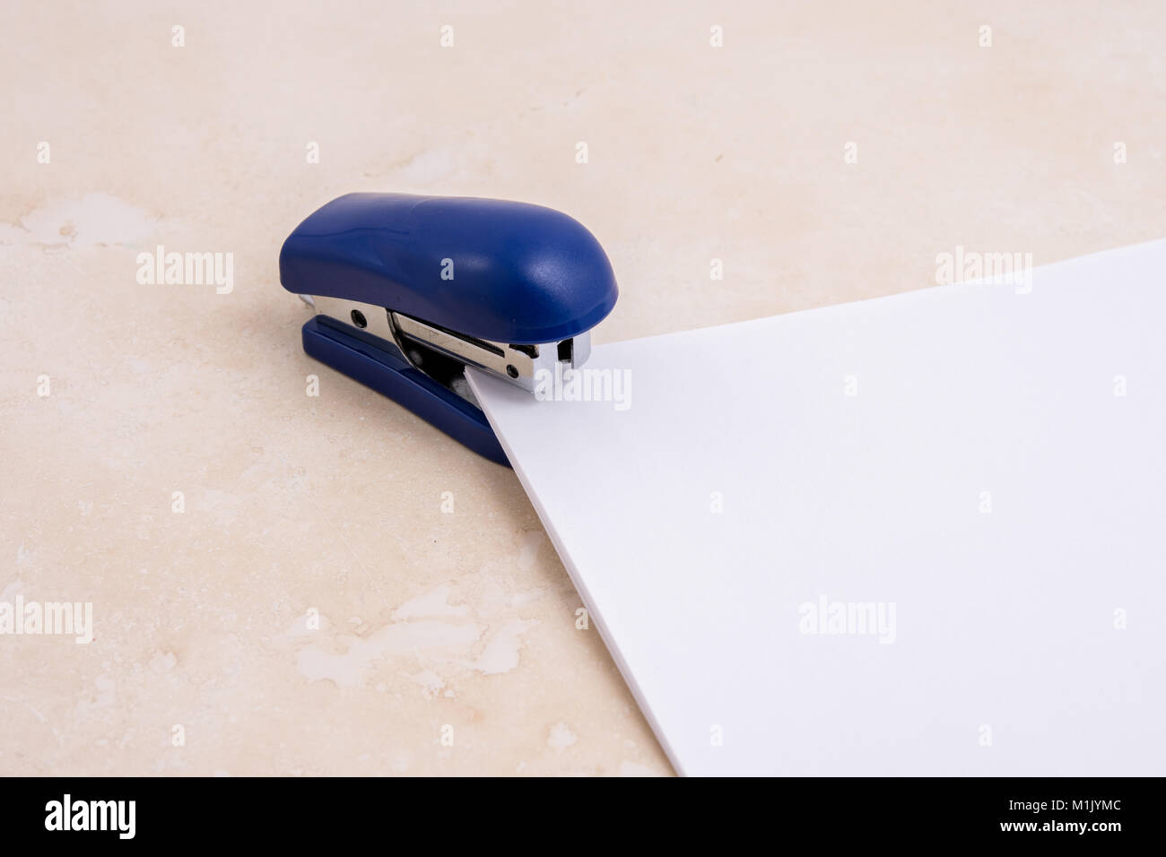 Small blue stapler with paper on stone background Stock Photo - Alamy