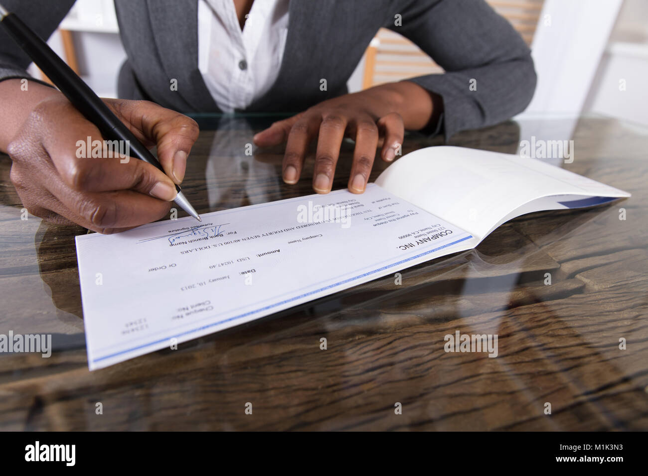 Close-up Of A Human Hand Signing Cheque On Desk Stock Photo - Alamy