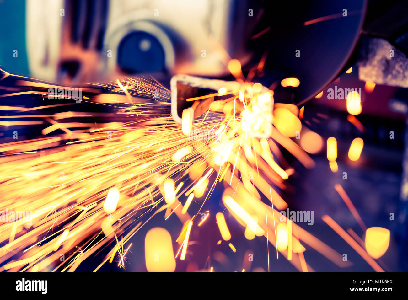Stream of sparks flying from metal being cut with electric grinder ...