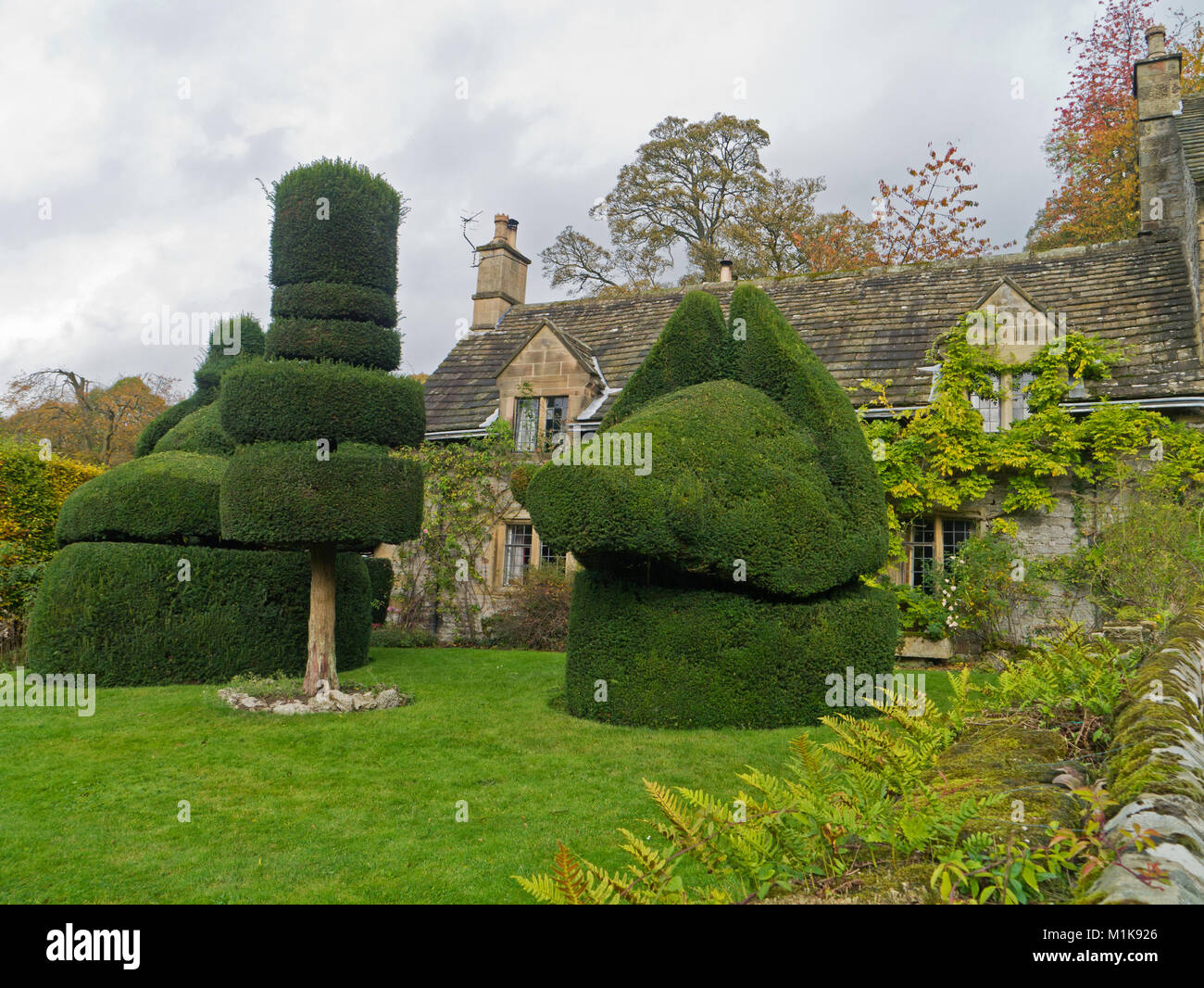 Assorted topiary, including a boar's head, in front of an old cottage ...