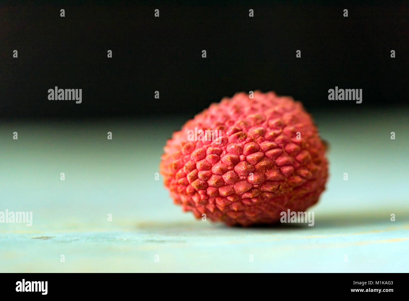 Single lychee on wooden background close Stock Photo - Alamy