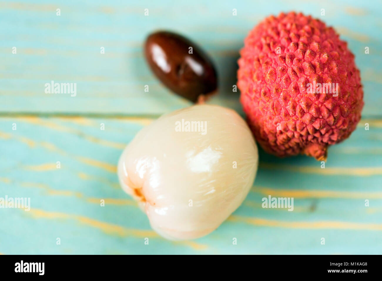 Two lychee fruits and seed wooden background Stock Photo - Alamy