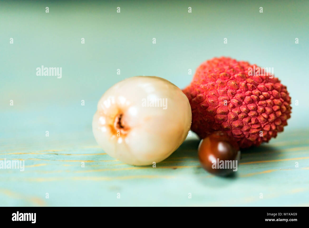 Two lychee fruits and seed wooden background Stock Photo - Alamy