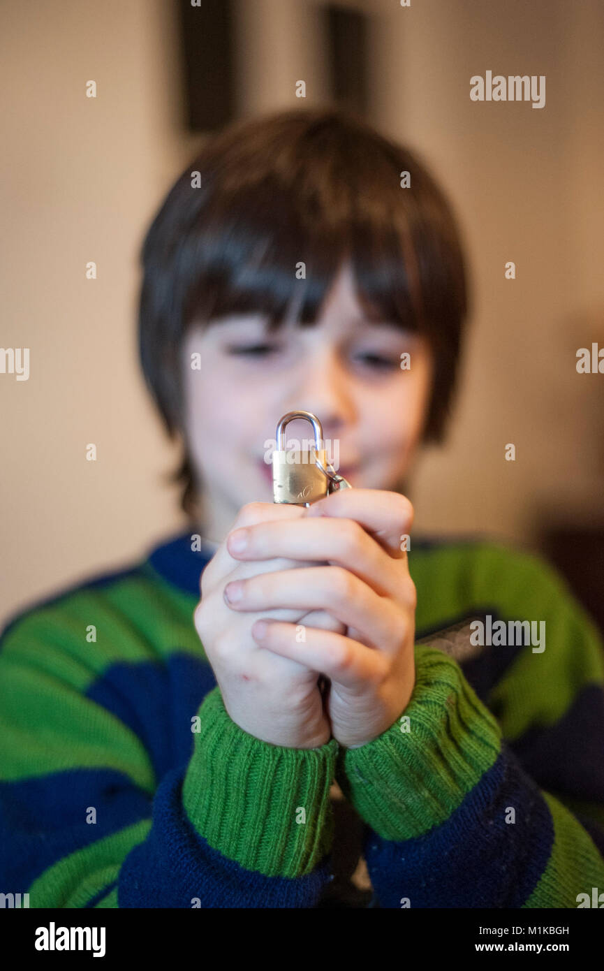 portrait of a 10 year old boy in his home showing a small padlock in ...