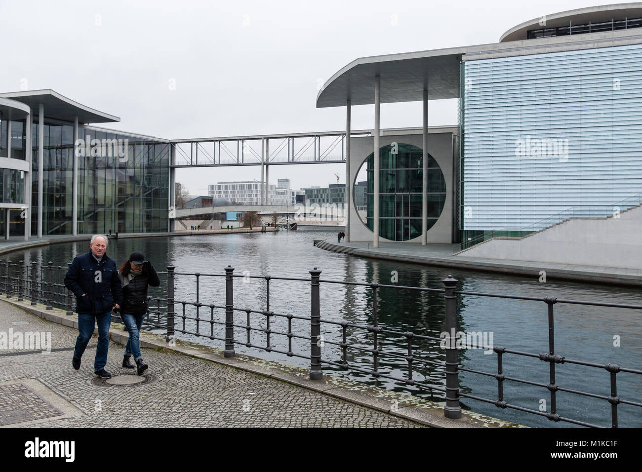 Couple walking along the River Spree with modern German parliament ...