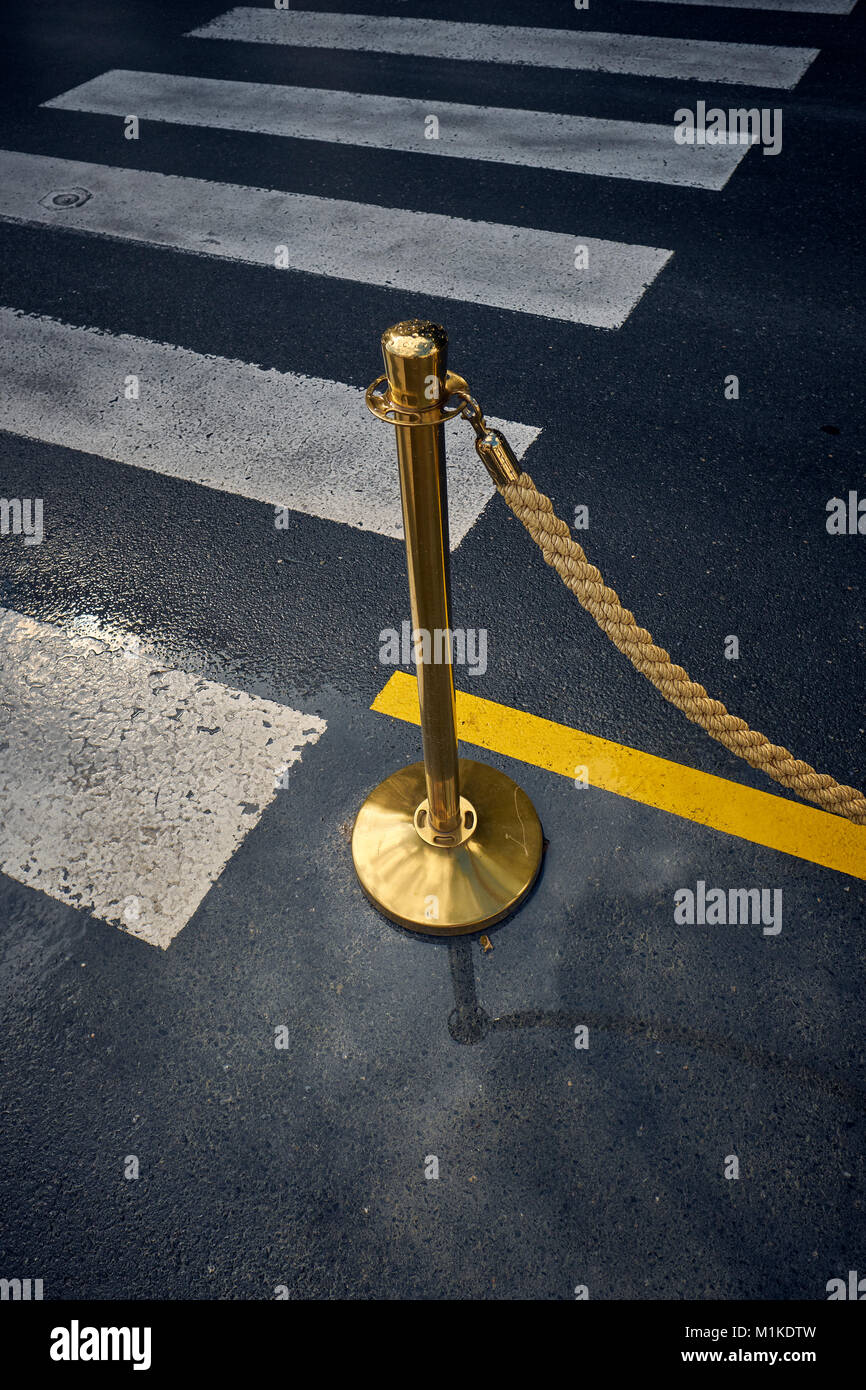 A gold rope barrier and stand at a pedestrian road crossing - special ...