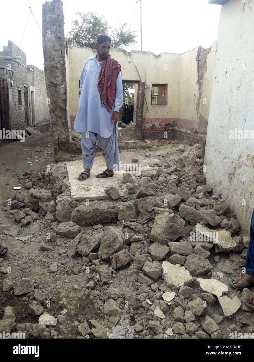 Lasbela. 31st Jan, 2018. A man looks at the damaged wall of his house ...