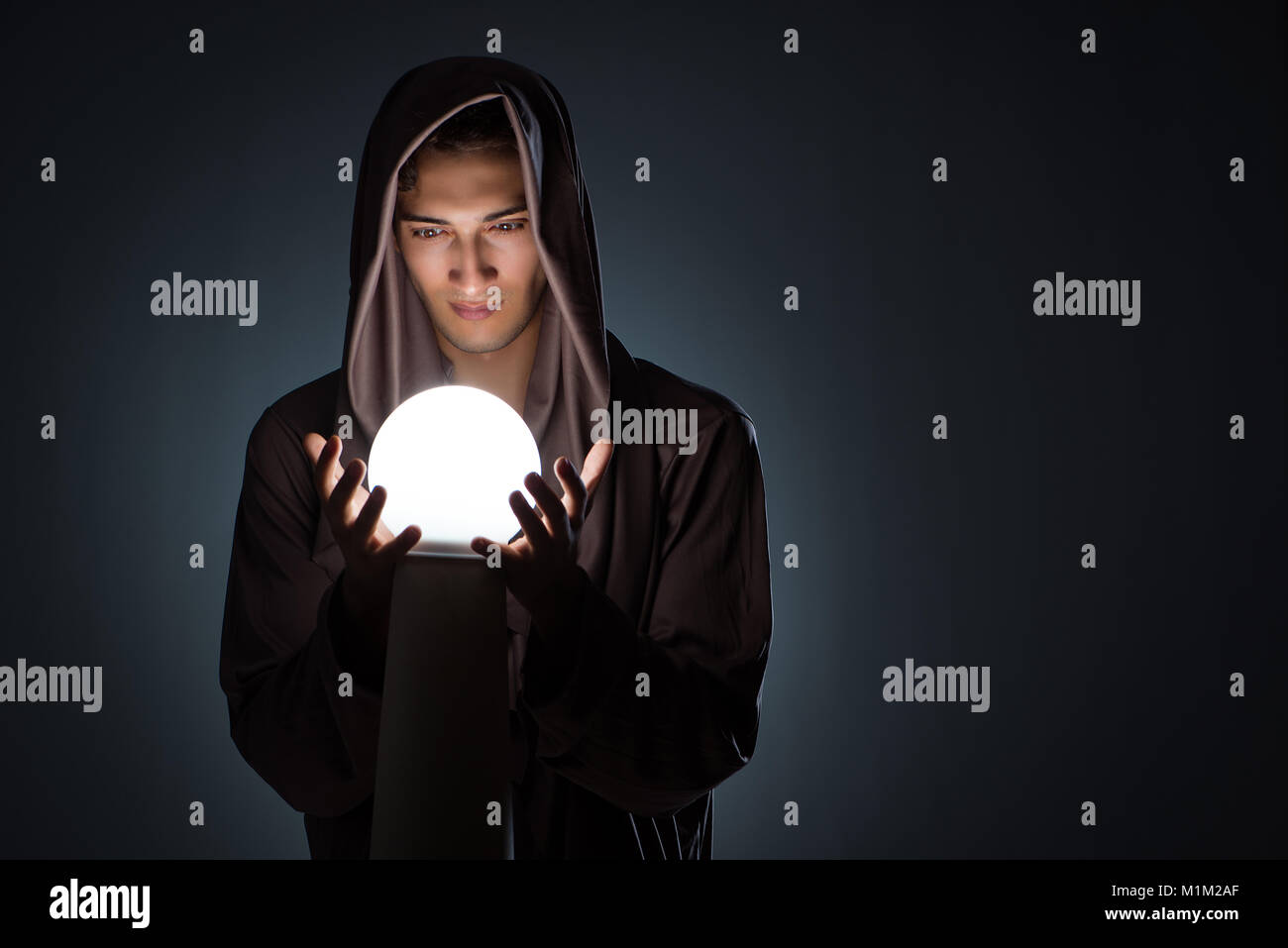 Young wizard with crystal ball in dark room Stock Photo - Alamy