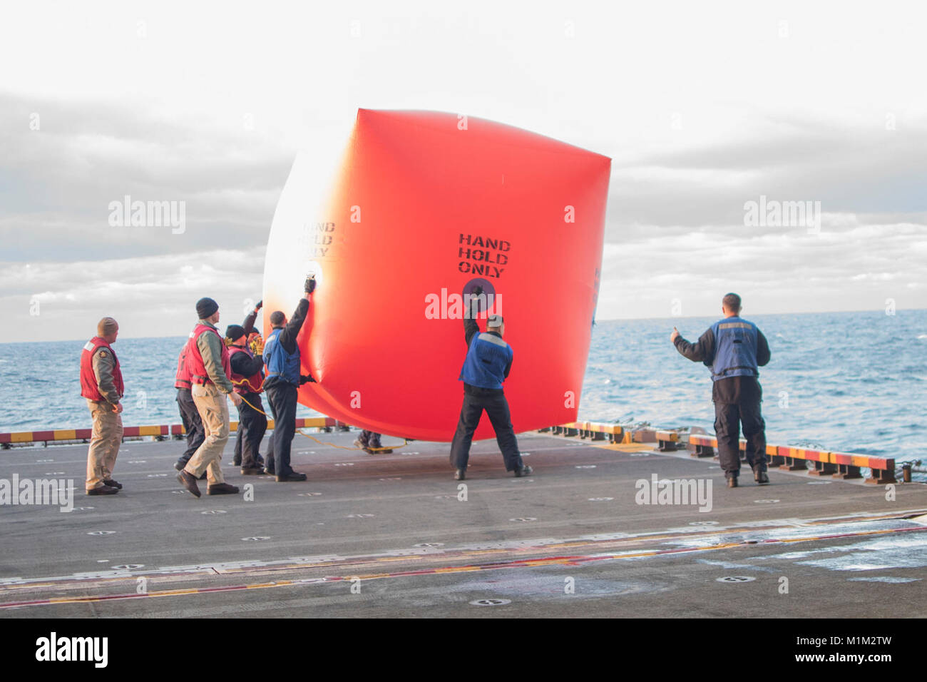U.S. Navy sailors launch red inflatable baloon target prior to gunnery ...