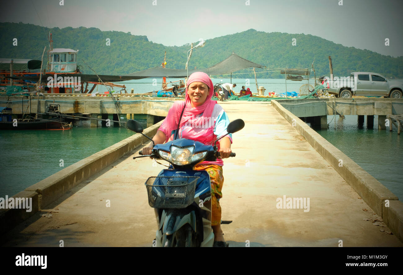 A local Muslim woman ride a motorcycle at a dock in koh Yao Yai, a Thai ...