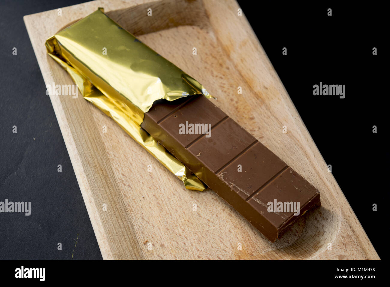slab of milk chocolate on a wooden dish and with black background Stock ...