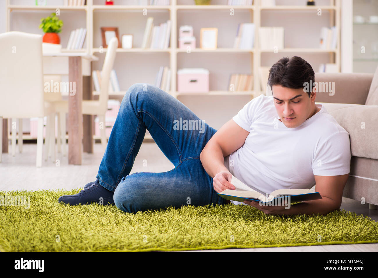 Man reading book at home on floor Stock Photo - Alamy