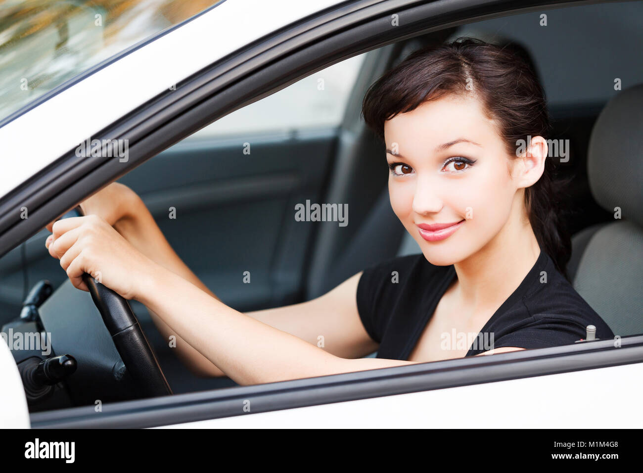 Pretty woman driver smiling to you from the white car Stock Photo - Alamy