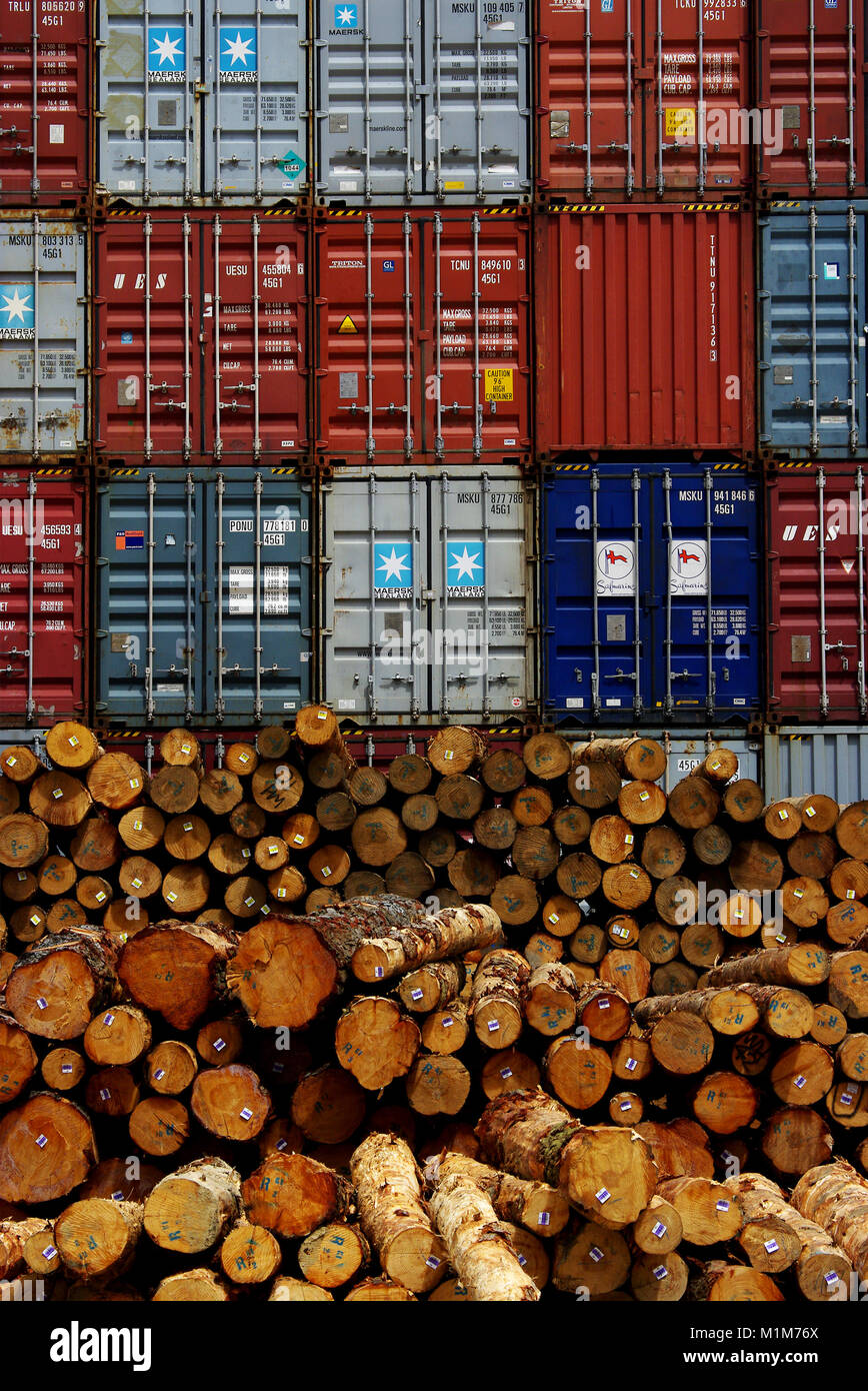 A pile of logs infront of a stack of shipping containers Stock Photo ...