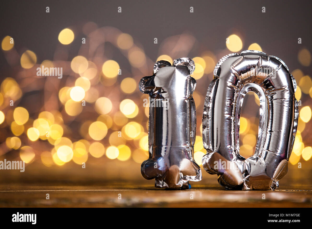Silver number 10 celebration foil balloon against blurred light ...