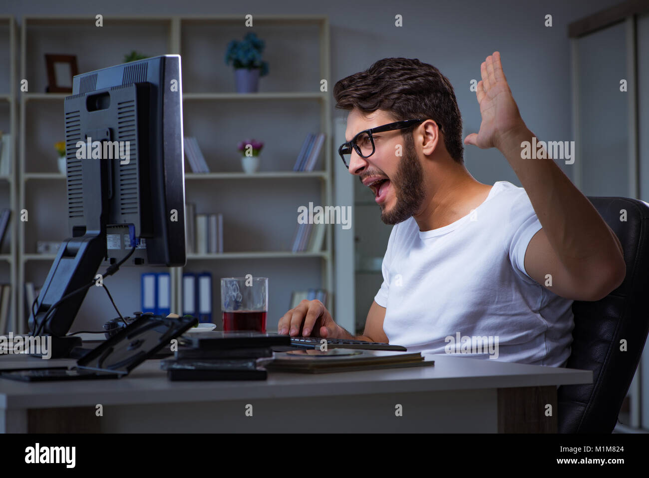 Young man staying late in office to do overtime work Stock Photo - Alamy