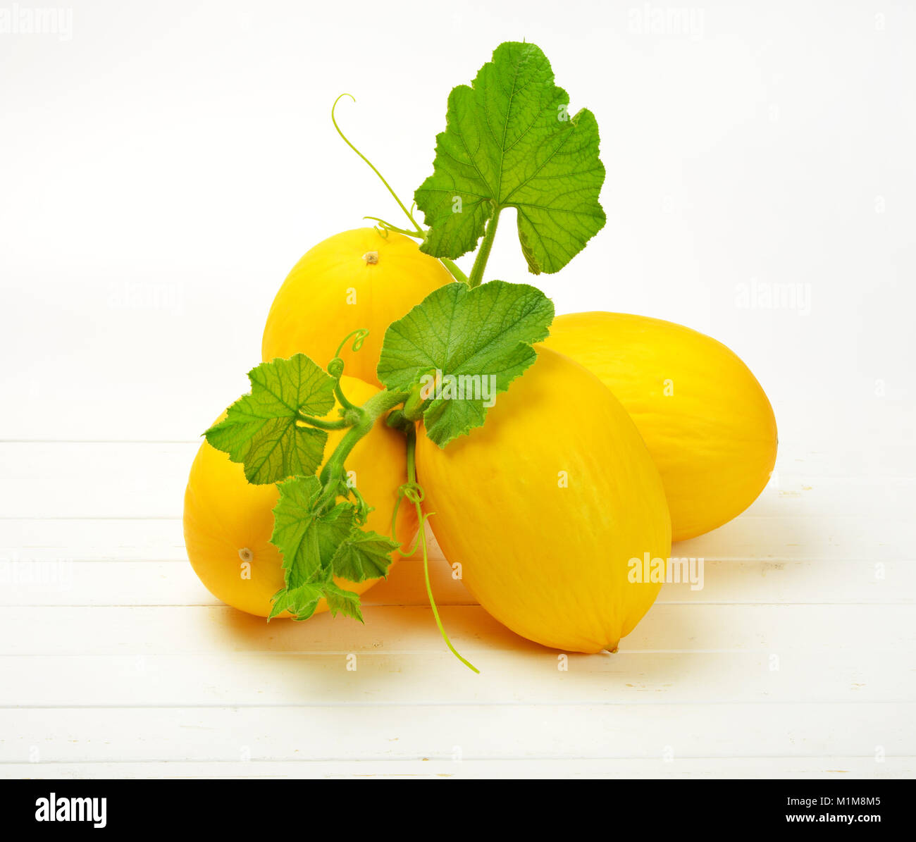 four whole yellow melons on white wooden background Stock Photo - Alamy