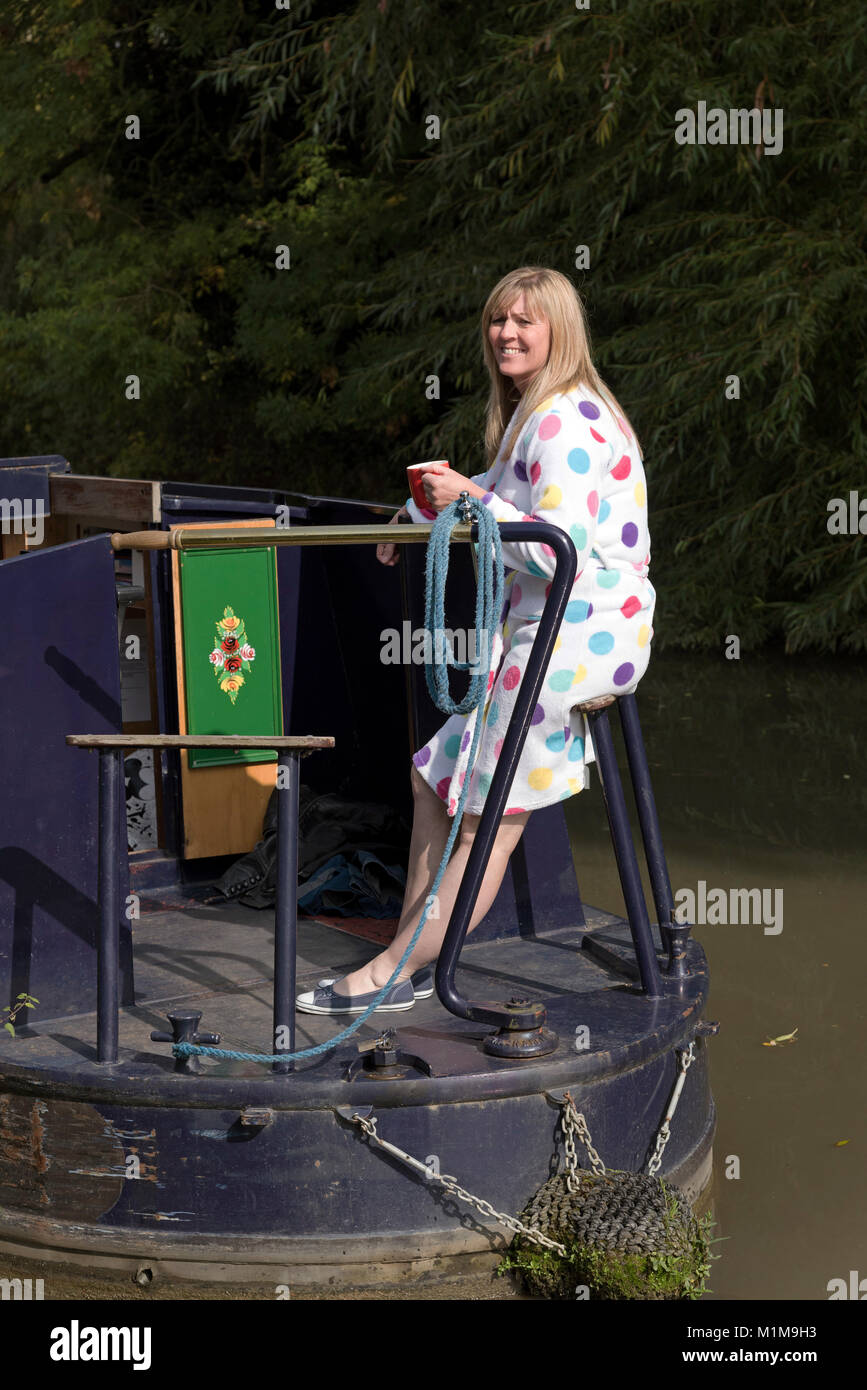 Holidaymaker standing on the deck of a narrowboat early in the morning ...