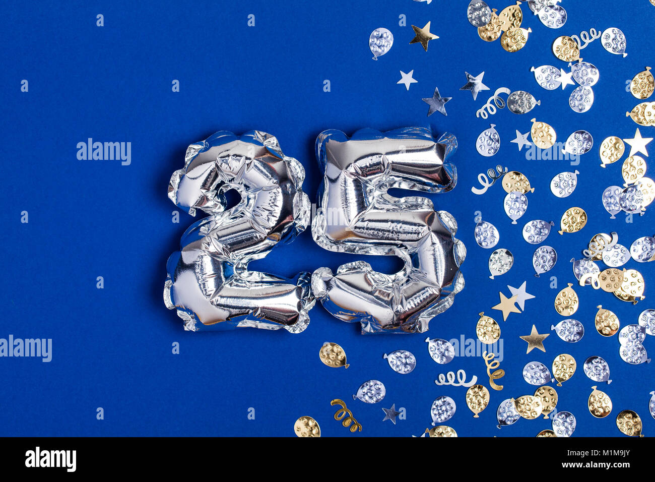 Silver foil number 25 balloon on a blue background with glitter ...