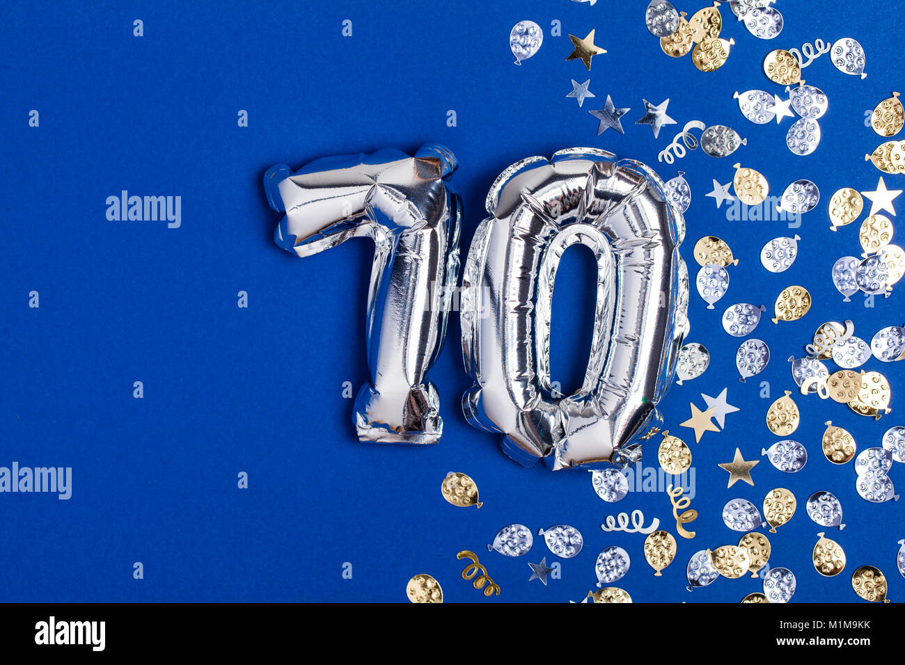 Silver foil number 70 balloon on a blue background with glitter ...