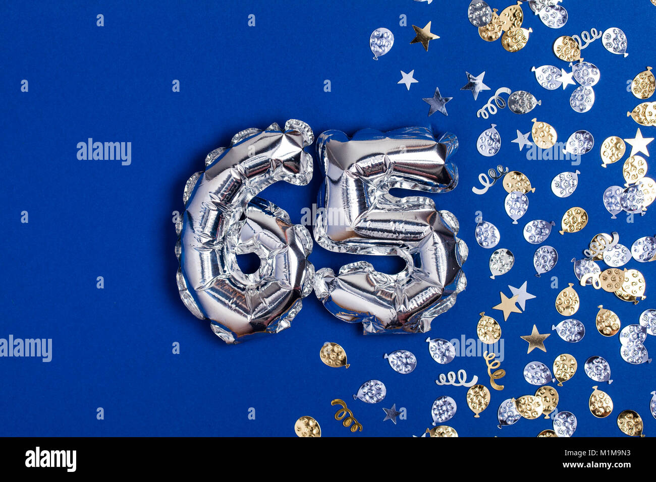 Silver foil number 65 balloon on a blue background with glitter ...