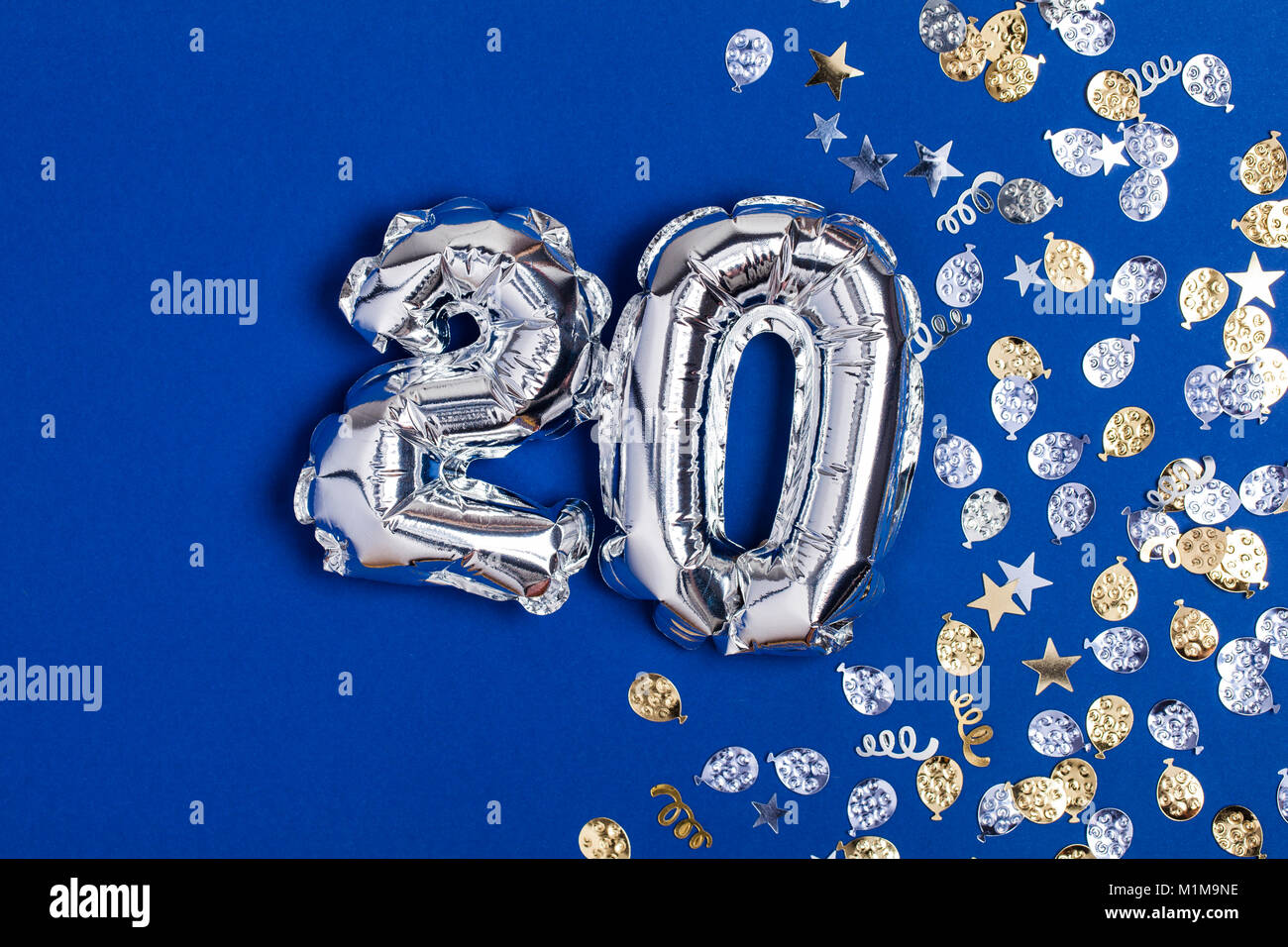 Silver foil number 20 balloon on a blue background with glitter ...