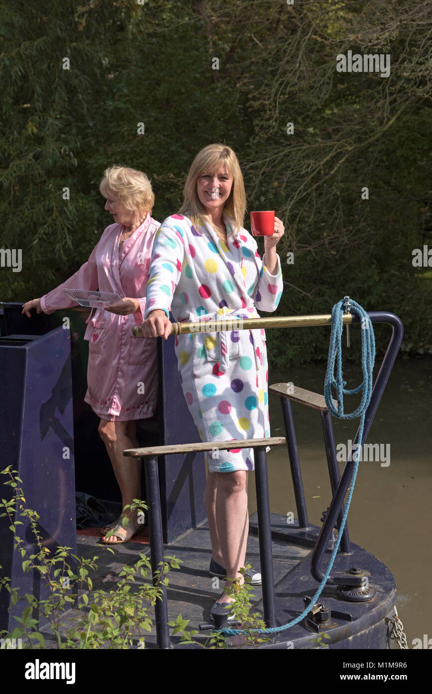 Holidaymaker standing on the deck of a narrowboat early in the morning ...