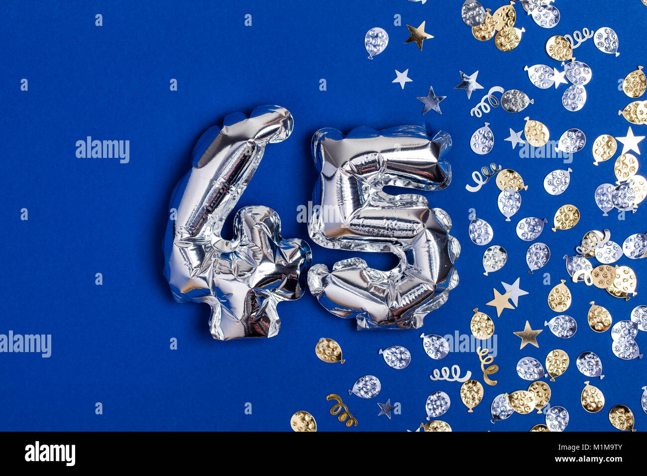 Silver foil number 45 balloon on a blue background with glitter ...