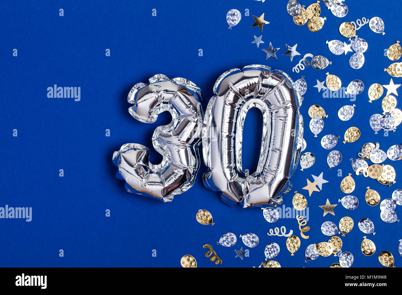 Silver foil number 30 balloon on a blue background with glitter ...