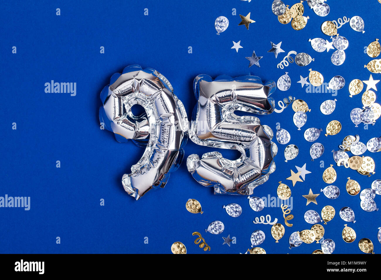Silver foil number 95 balloon on a blue background with glitter ...