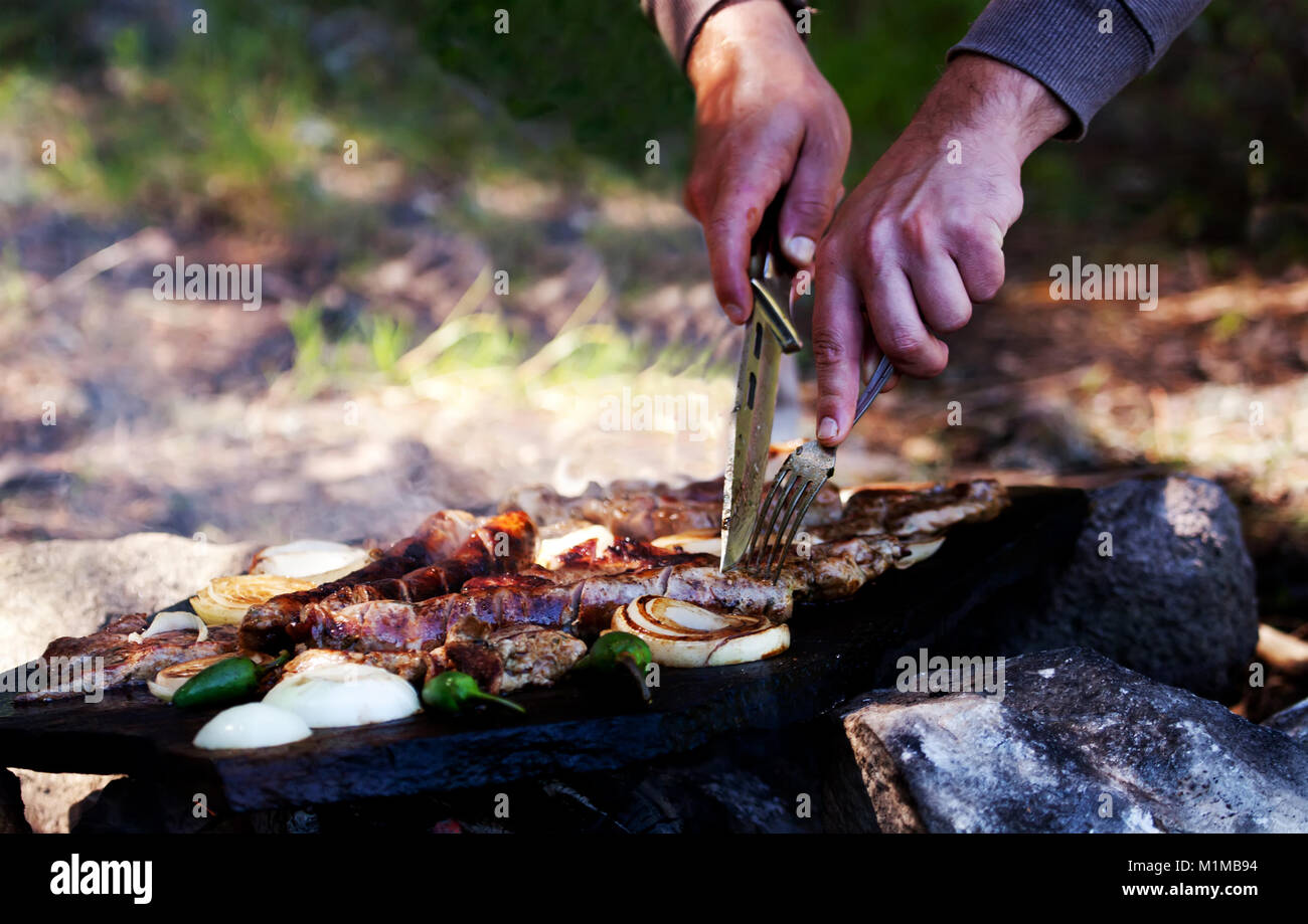Man cooking marinated tasty bbq on stone plate in the forest Stock ...
