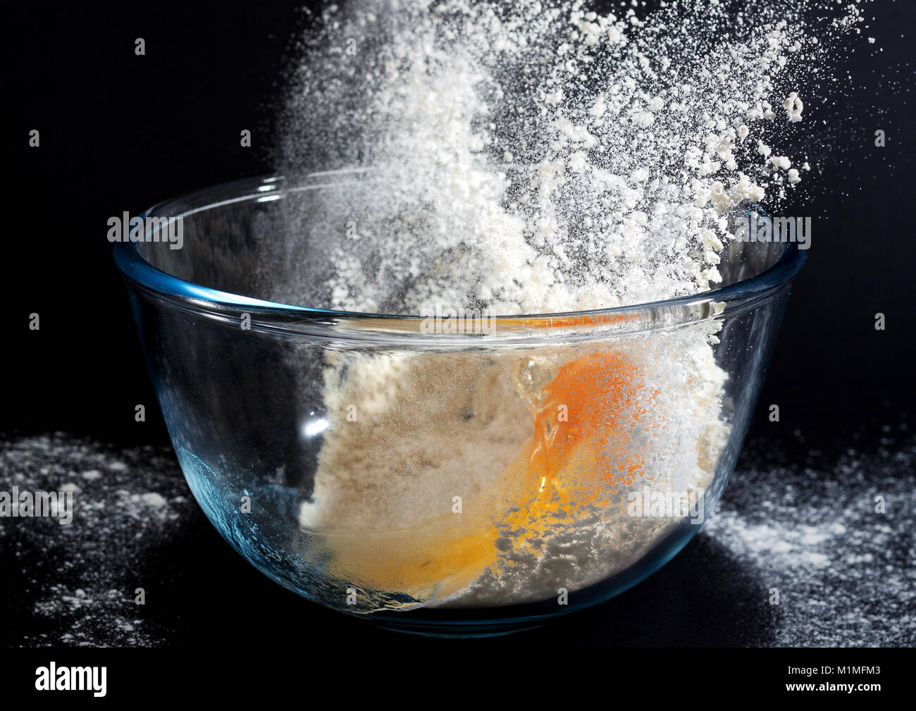 Egg dropped into flour and creating motion Stock Photo - Alamy
