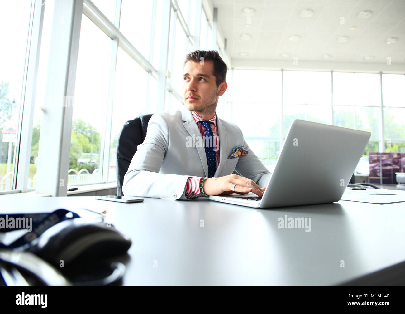 Portrait of young man sitting at his desk in the office Stock Photo - Alamy