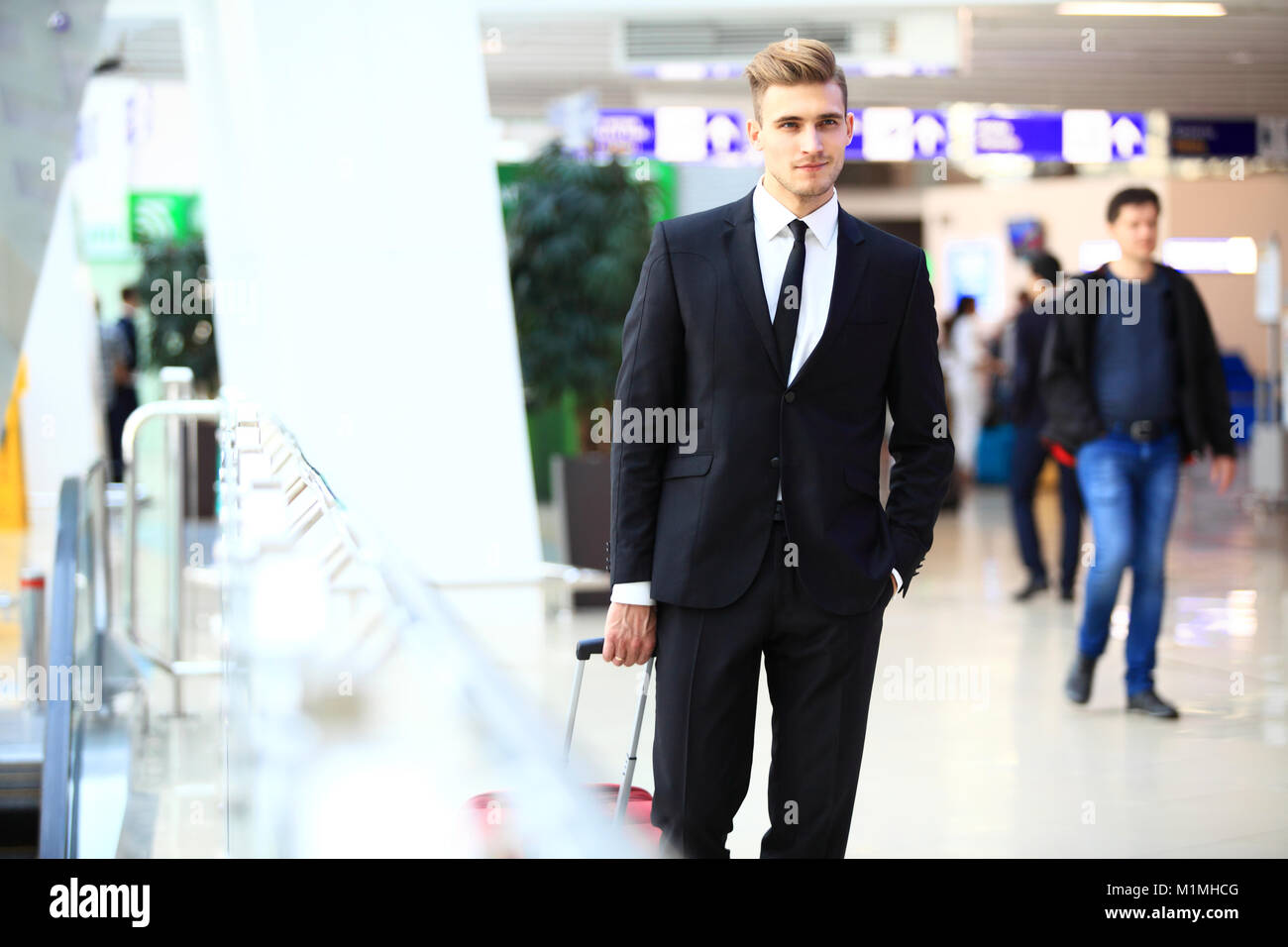 Business man at airport with suitcase Stock Photo - Alamy