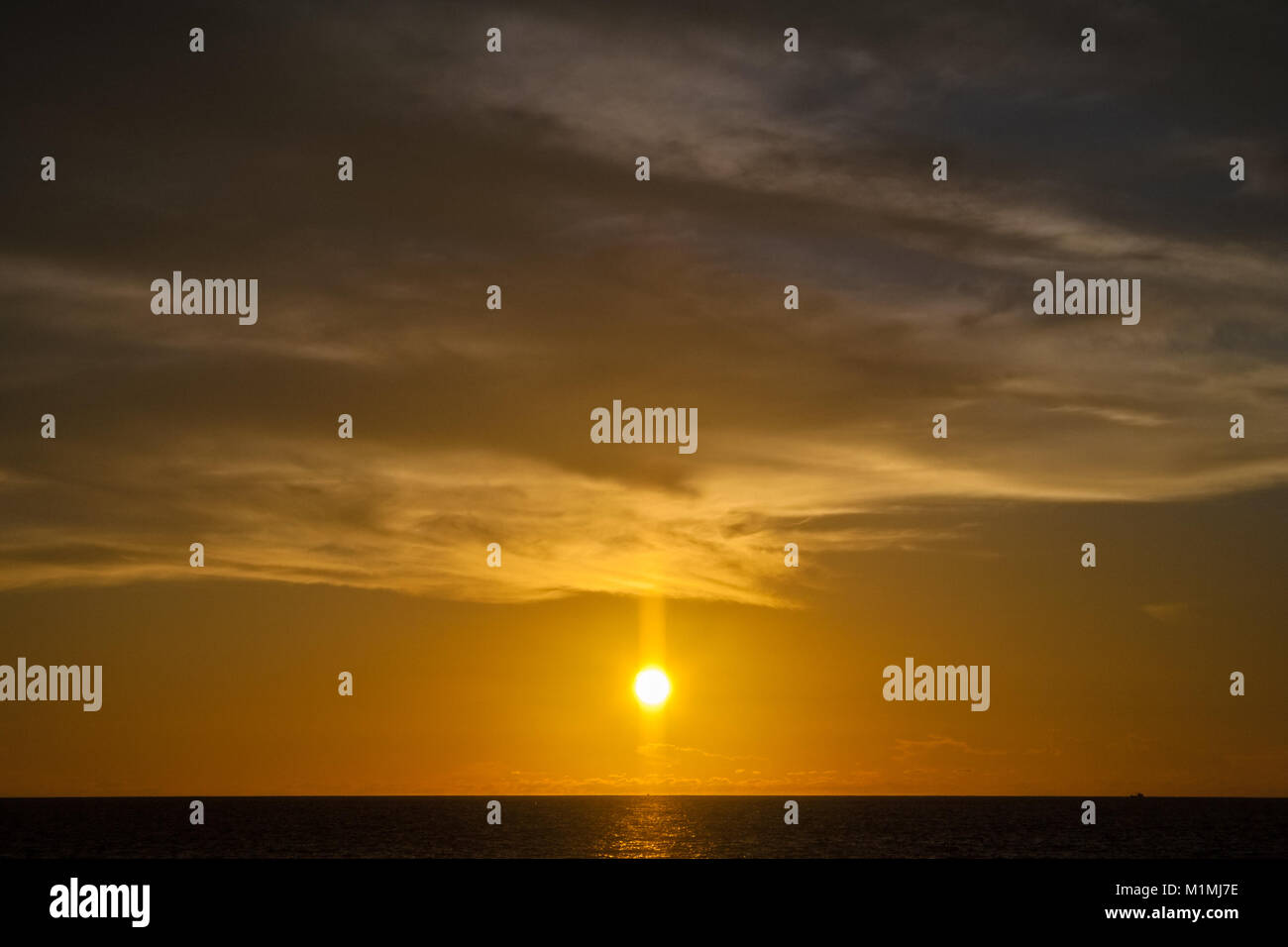 A special sunset; the sun is setting between a straight line horizon ...