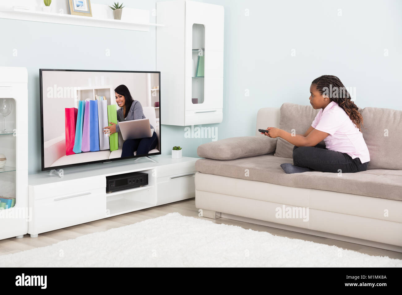 Girl Sitting On Couch Using Remote Control While Watching Television At ...